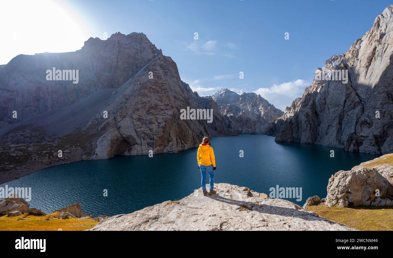 Tourist at the blue mountain lake between rocky steep mountain peaks ...