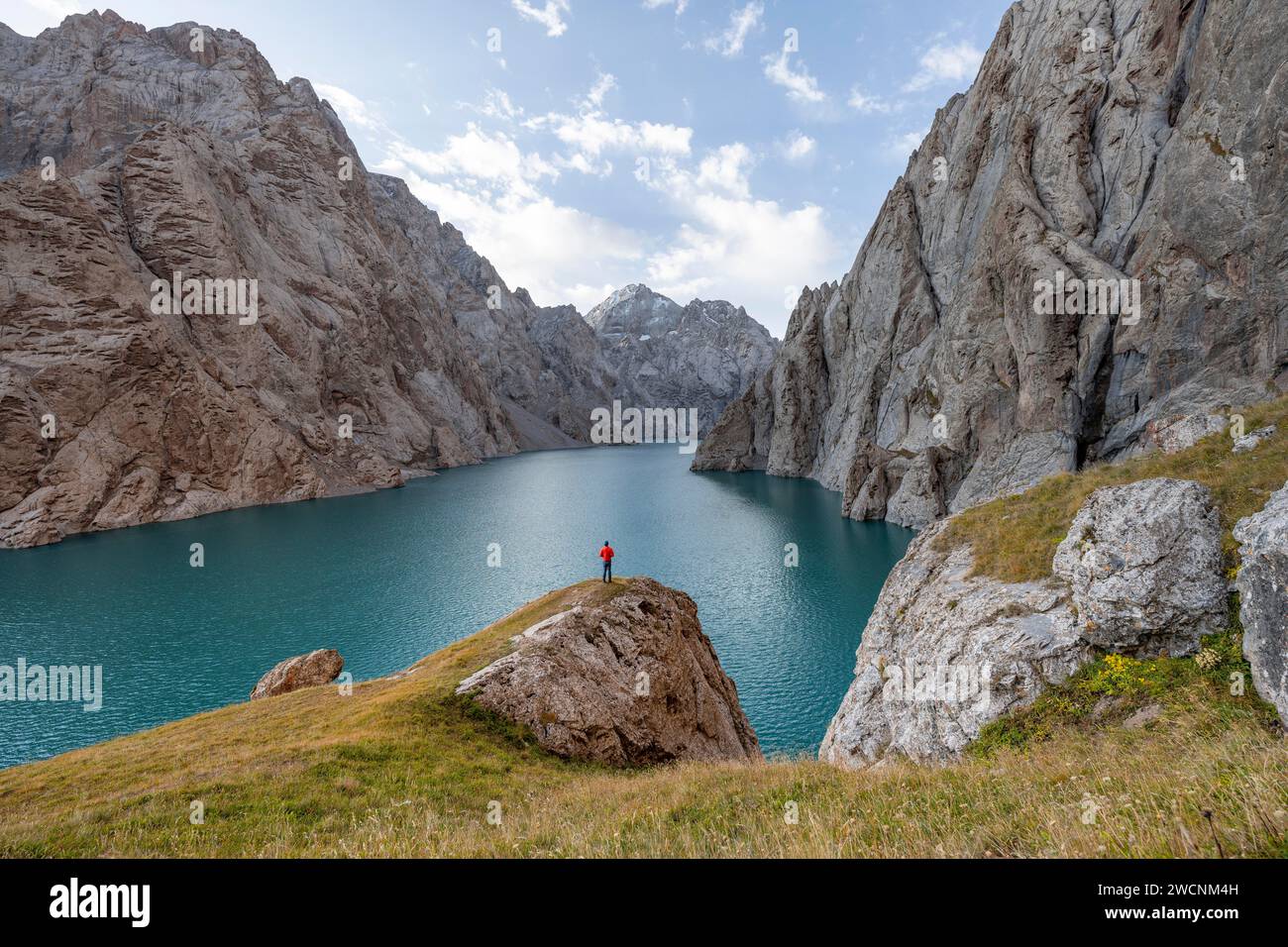 Tourist at the blue mountain lake between rocky steep mountain peaks ...
