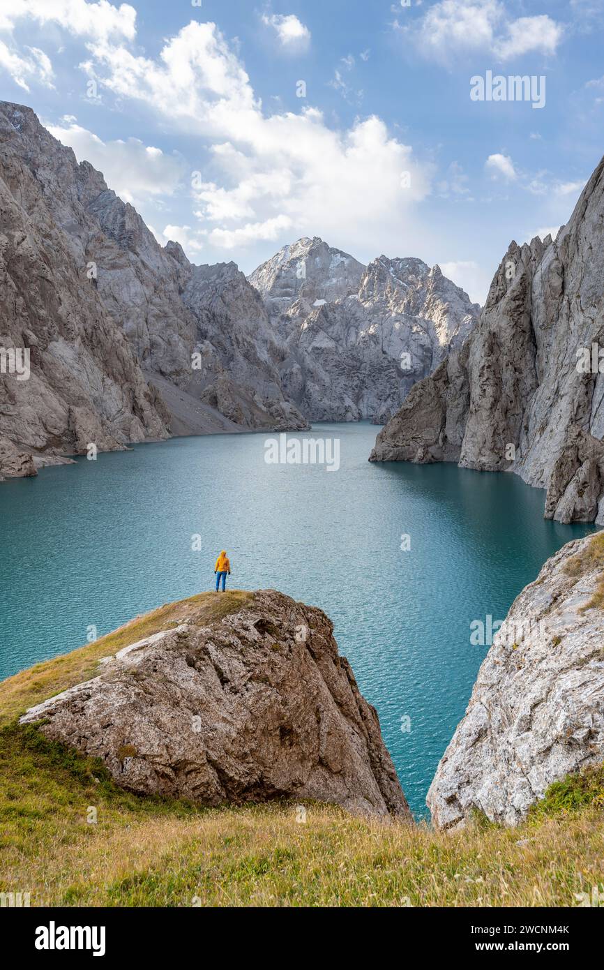 Tourist at the blue mountain lake between rocky steep mountain peaks ...