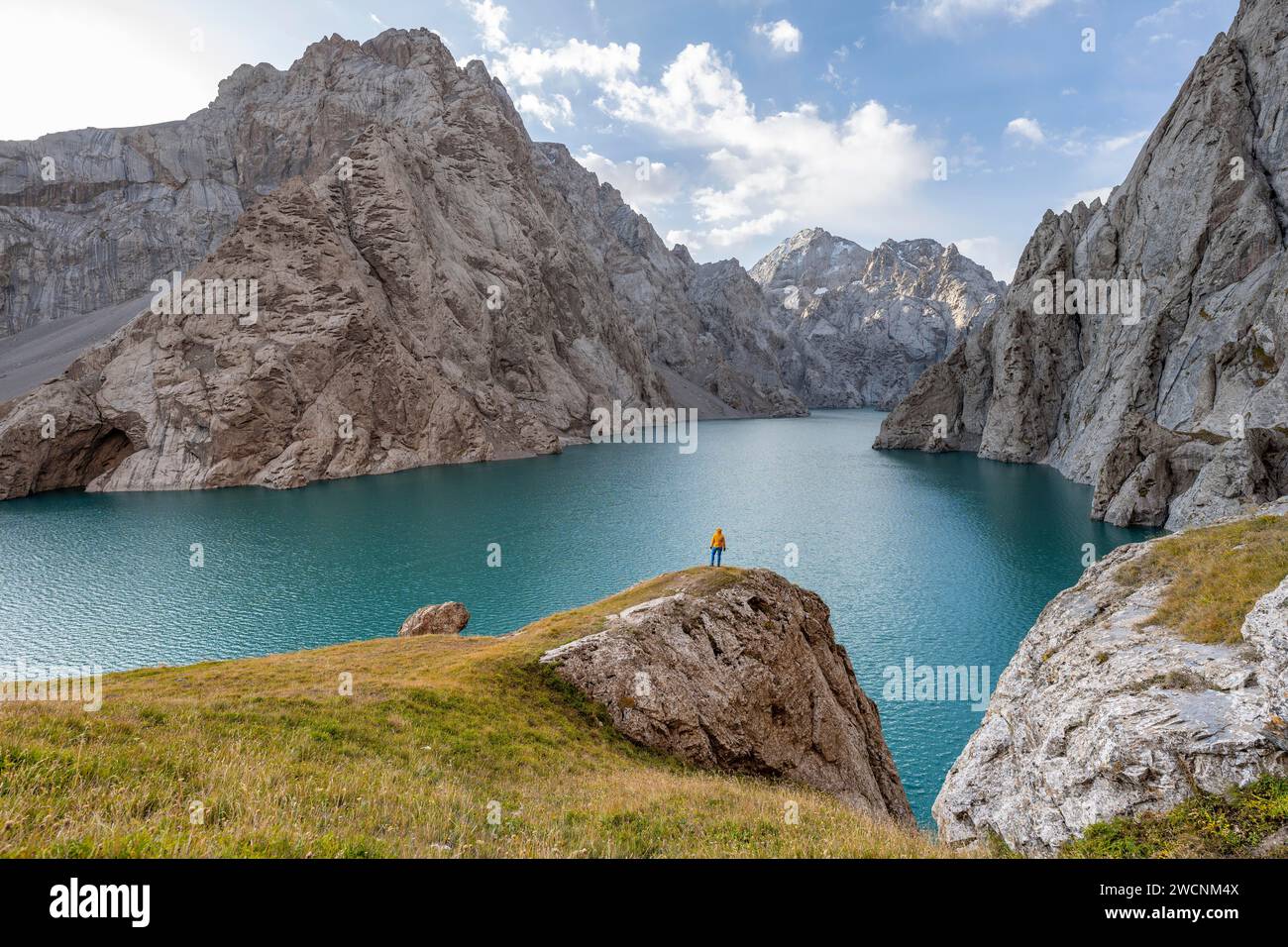 Tourist at the blue mountain lake between rocky steep mountain peaks ...