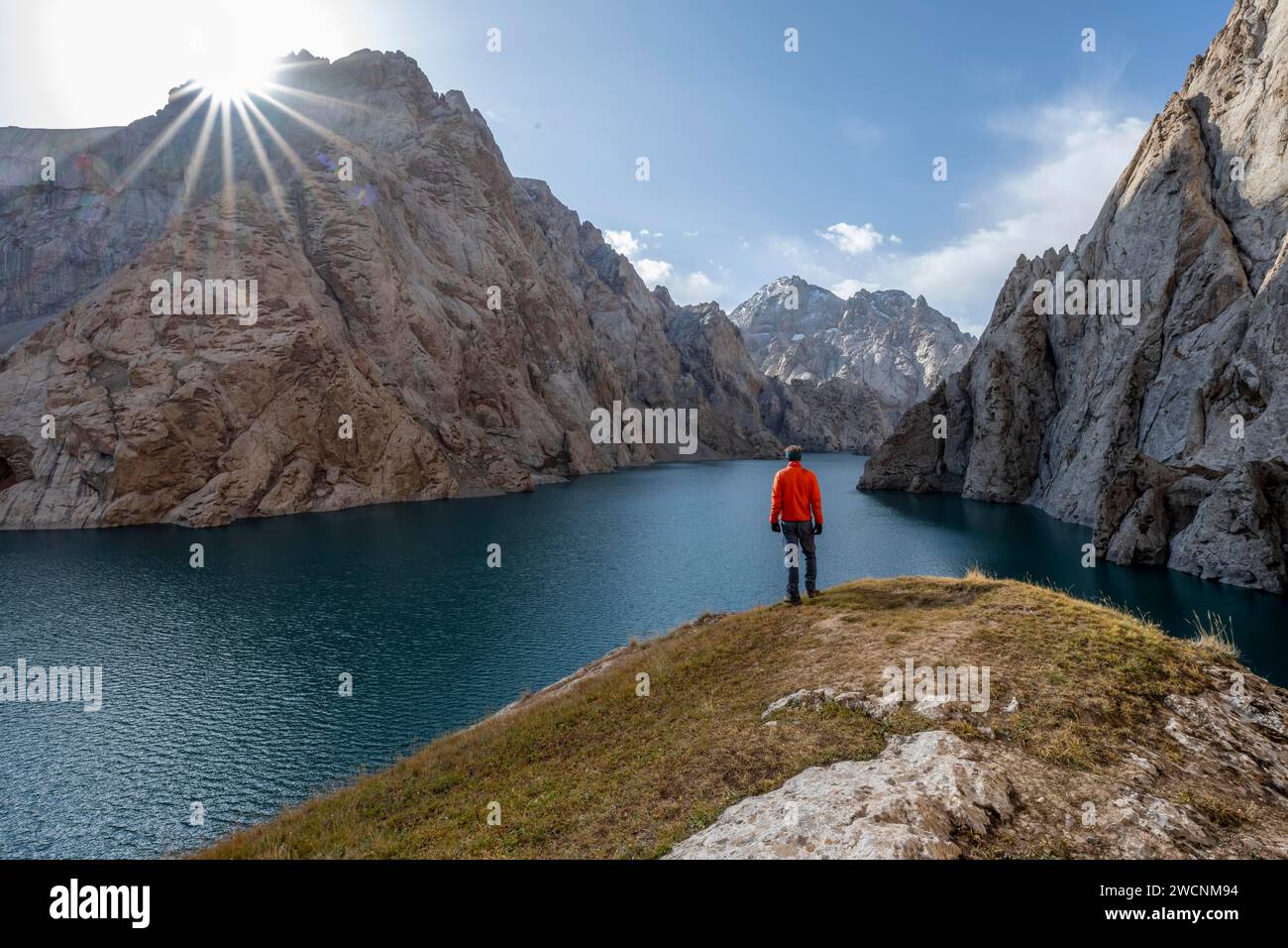 Tourist at the blue mountain lake between rocky steep mountain peaks ...