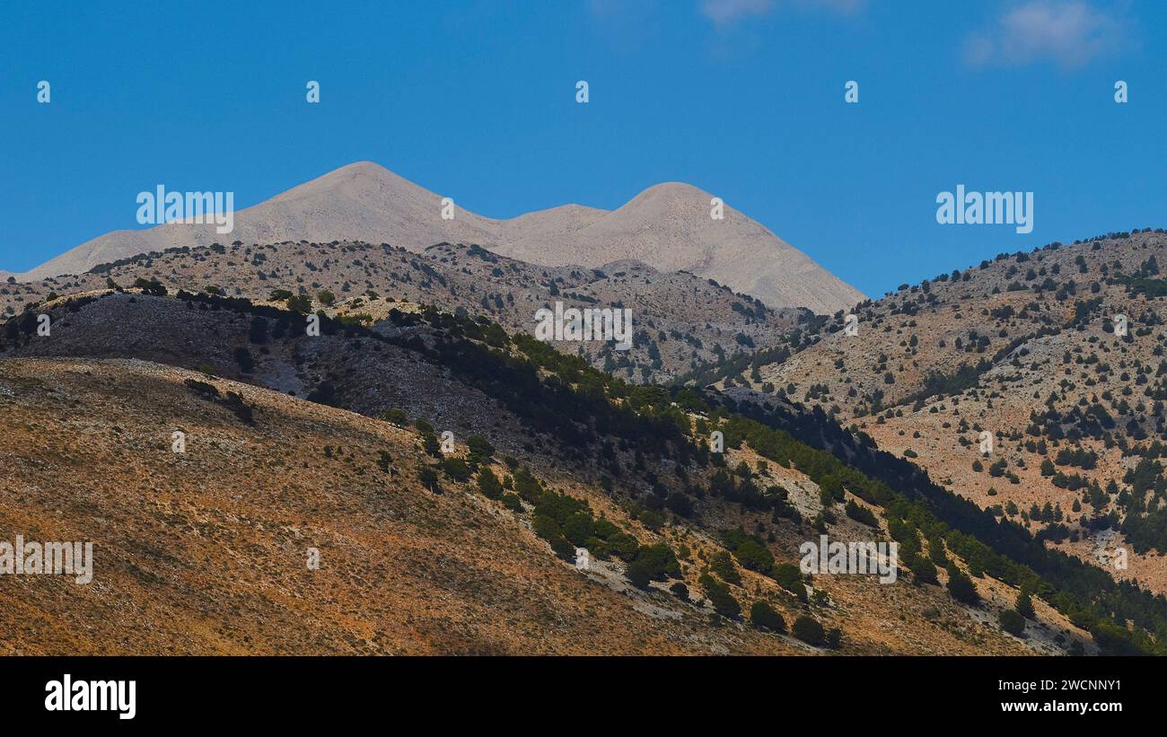 Curved mountains under a slightly cloudy sky and sparse vegetation ...