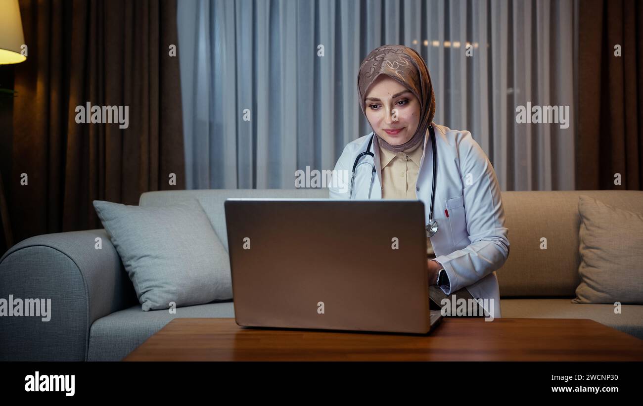 Female doctor in headscarf wears white coat talking to patient using ...