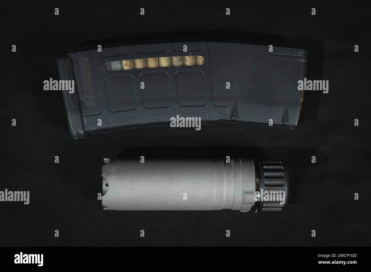 A loaded magazine with cartridges and a rifle silencer, close-up photo ...