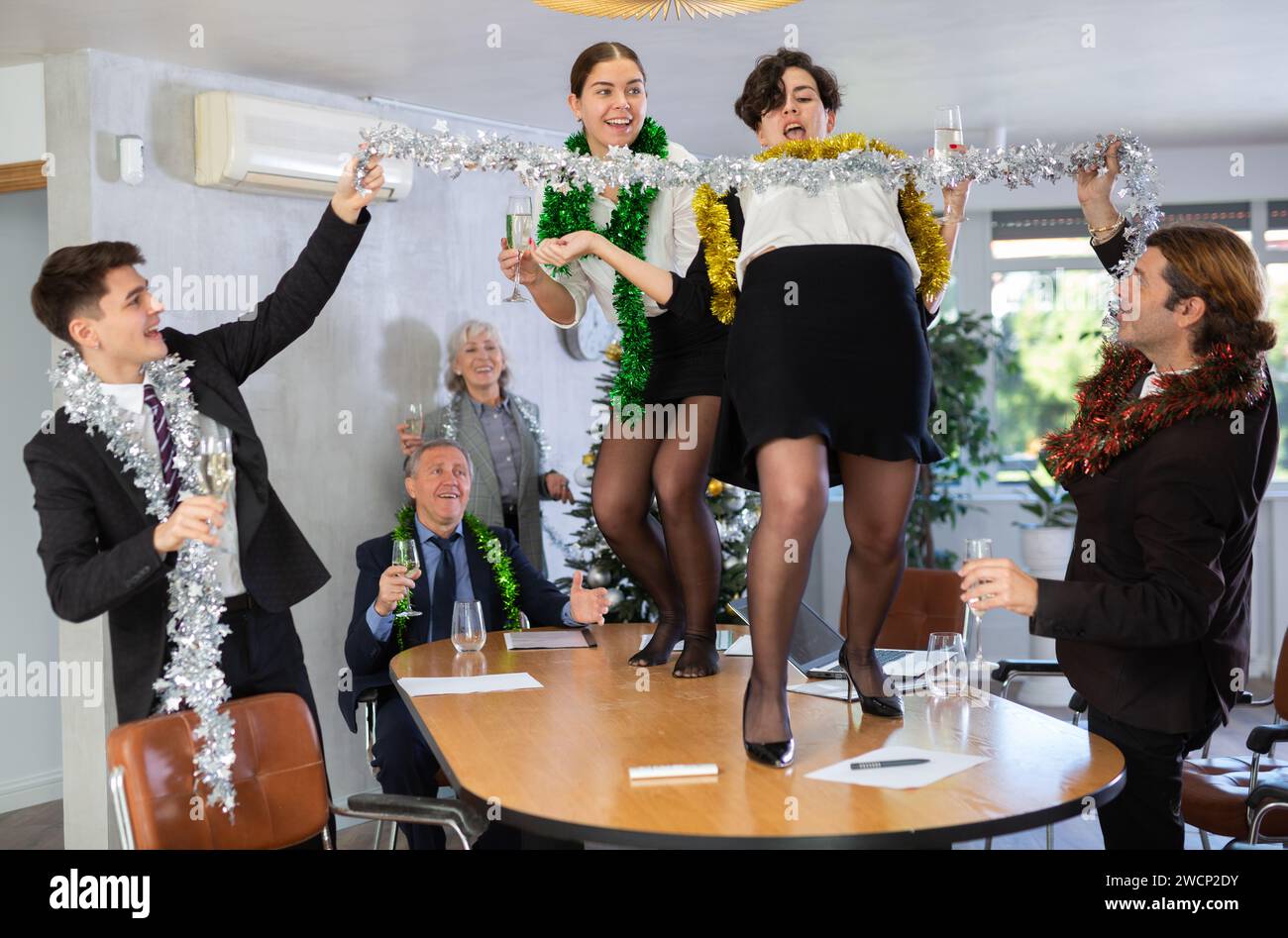 Excited girls dancing on table during New Year corporate party Stock ...