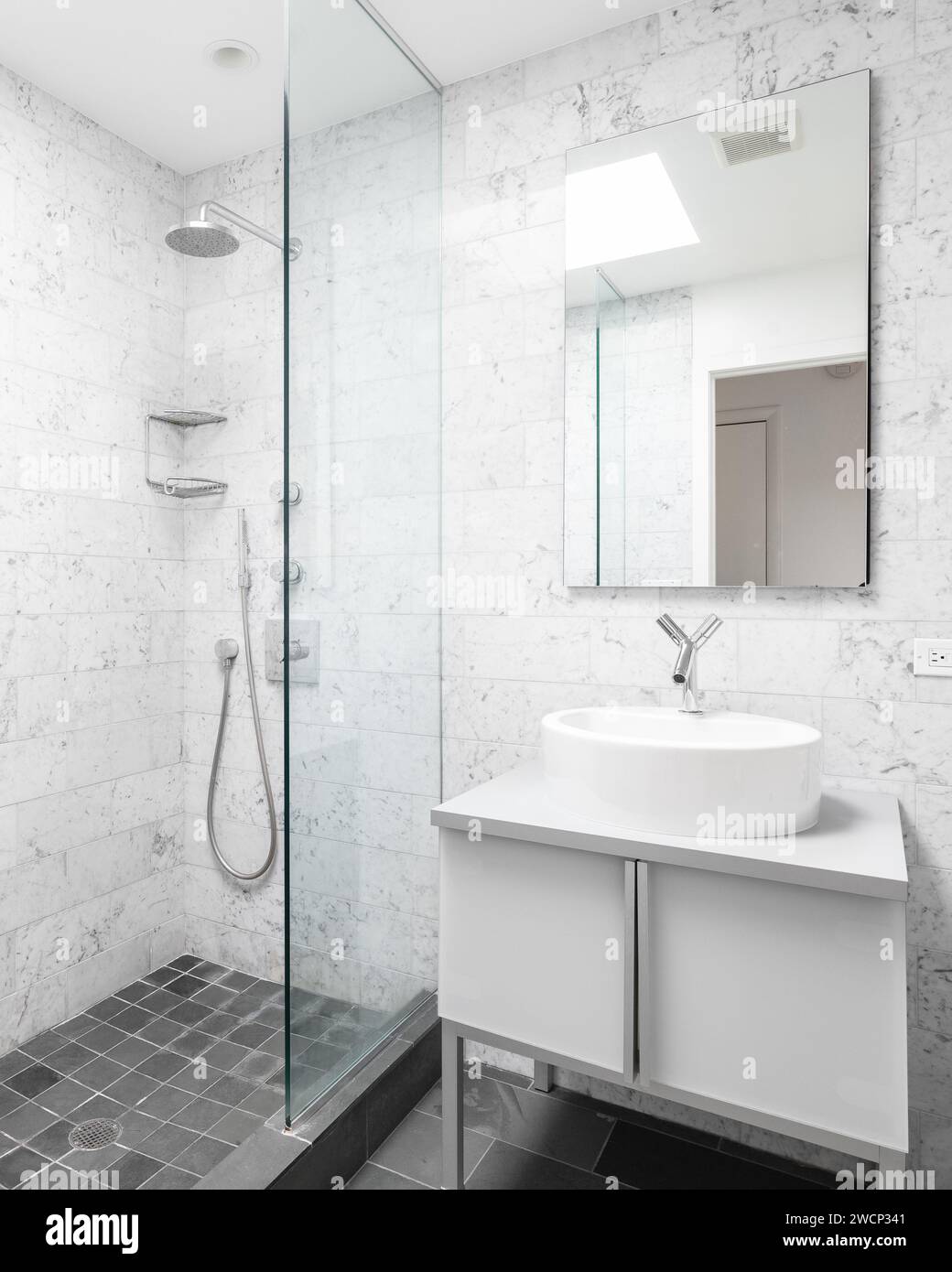A bathroom detail with a vessel sink on a white cabinet, marble tile ...