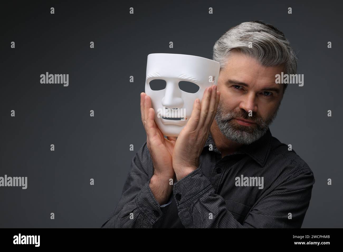 Multiple personality concept. Man with mask on dark grey background ...