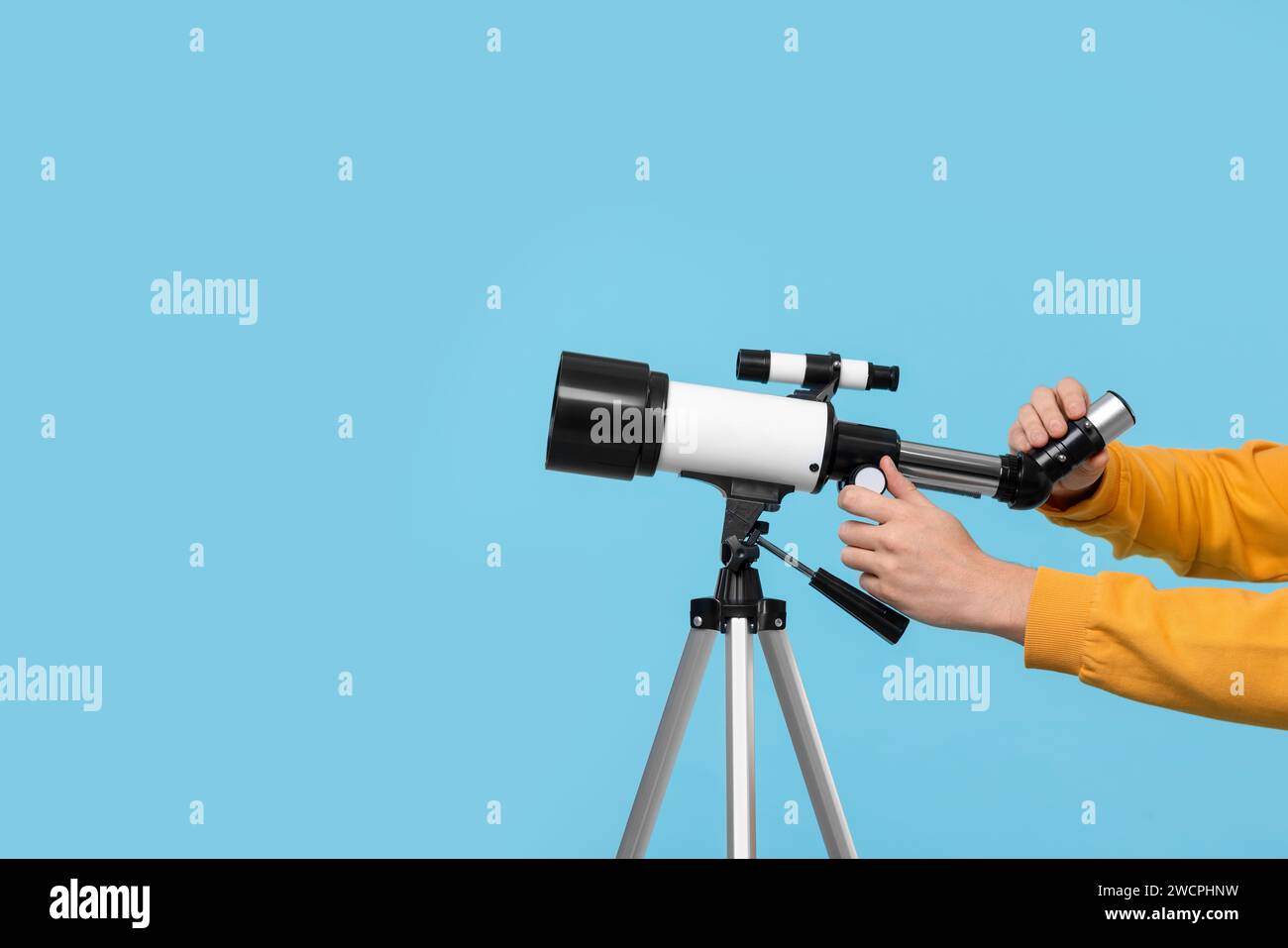 Astronomer setting up telescope on light blue background, closeup ...