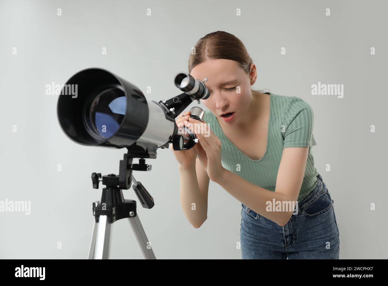 Young astronomer looking at stars through telescope on grey background ...