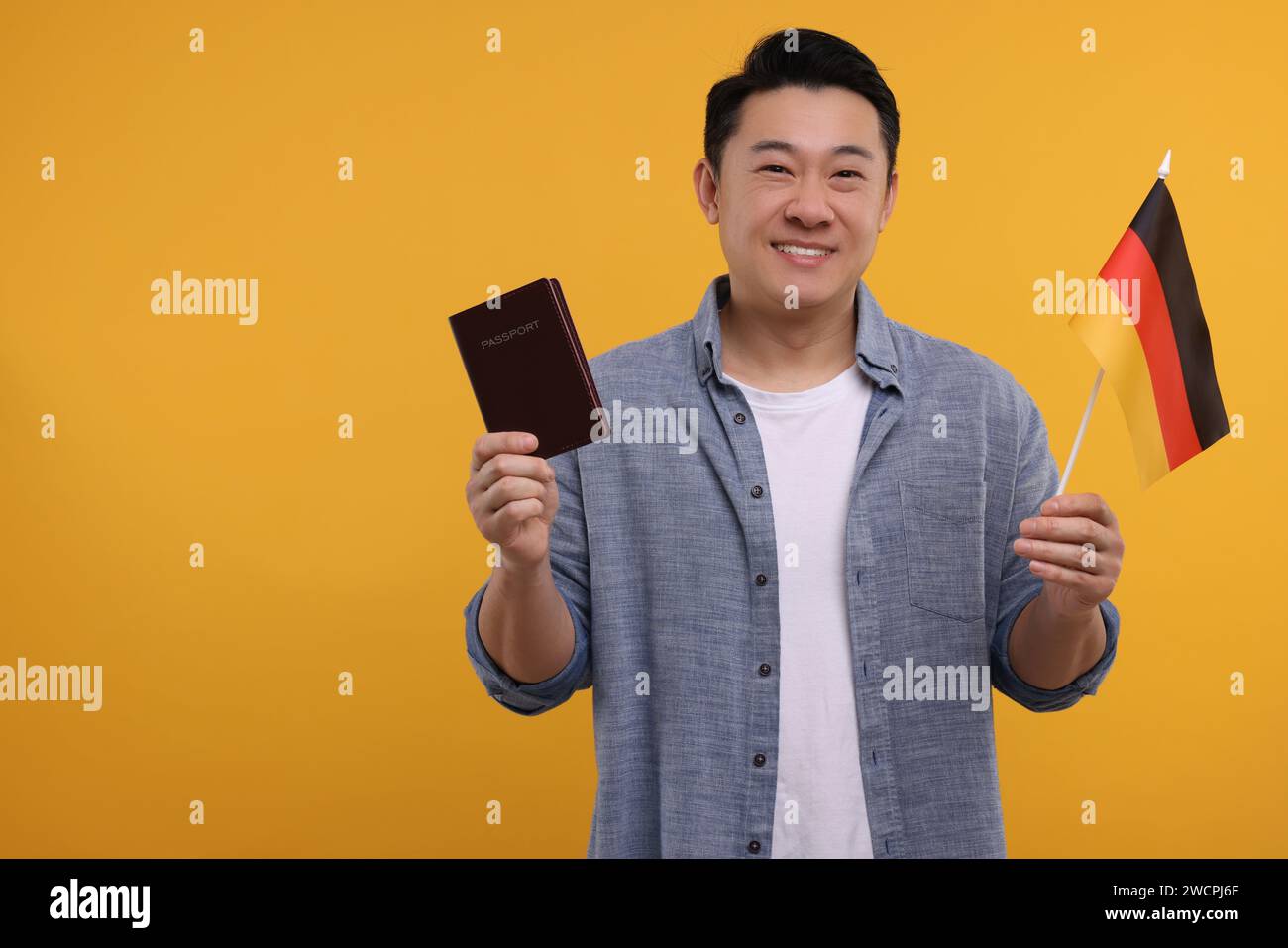 Immigration. Happy man with passport and flag of Germany on orange ...