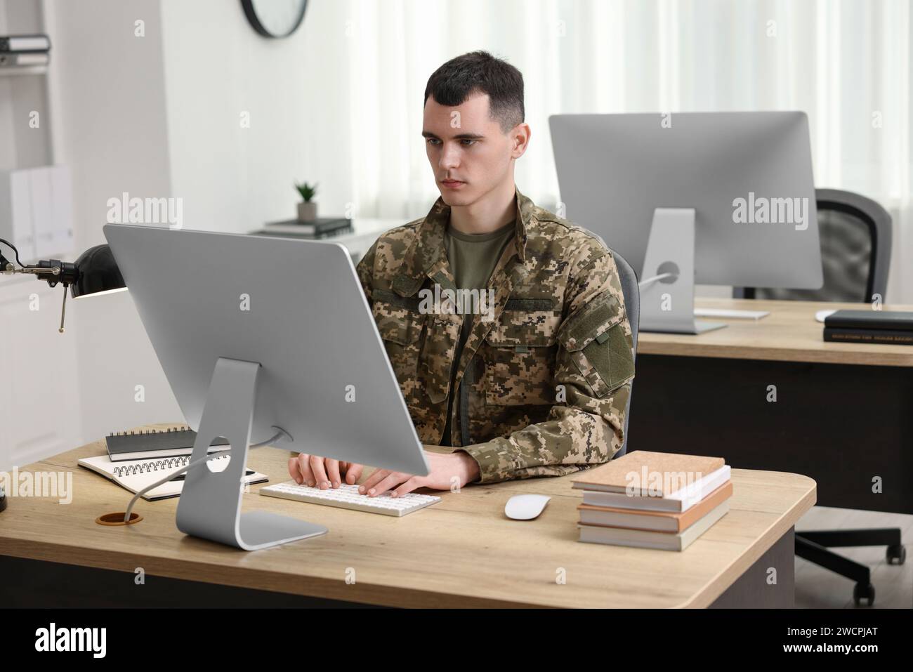 Military education. Young student in soldier uniform learning at wooden ...