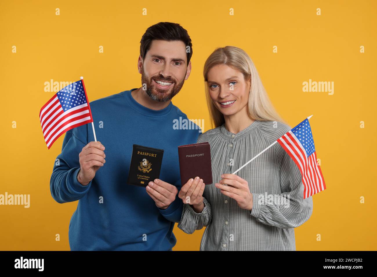 Immigration. Happy couple with passports and American flags on orange ...