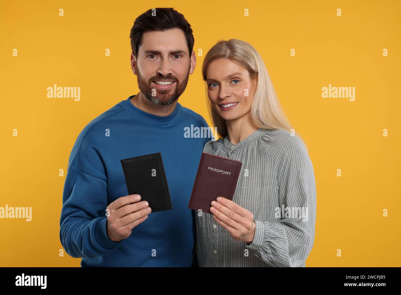 Immigration. Happy man and woman with passports on orange background ...