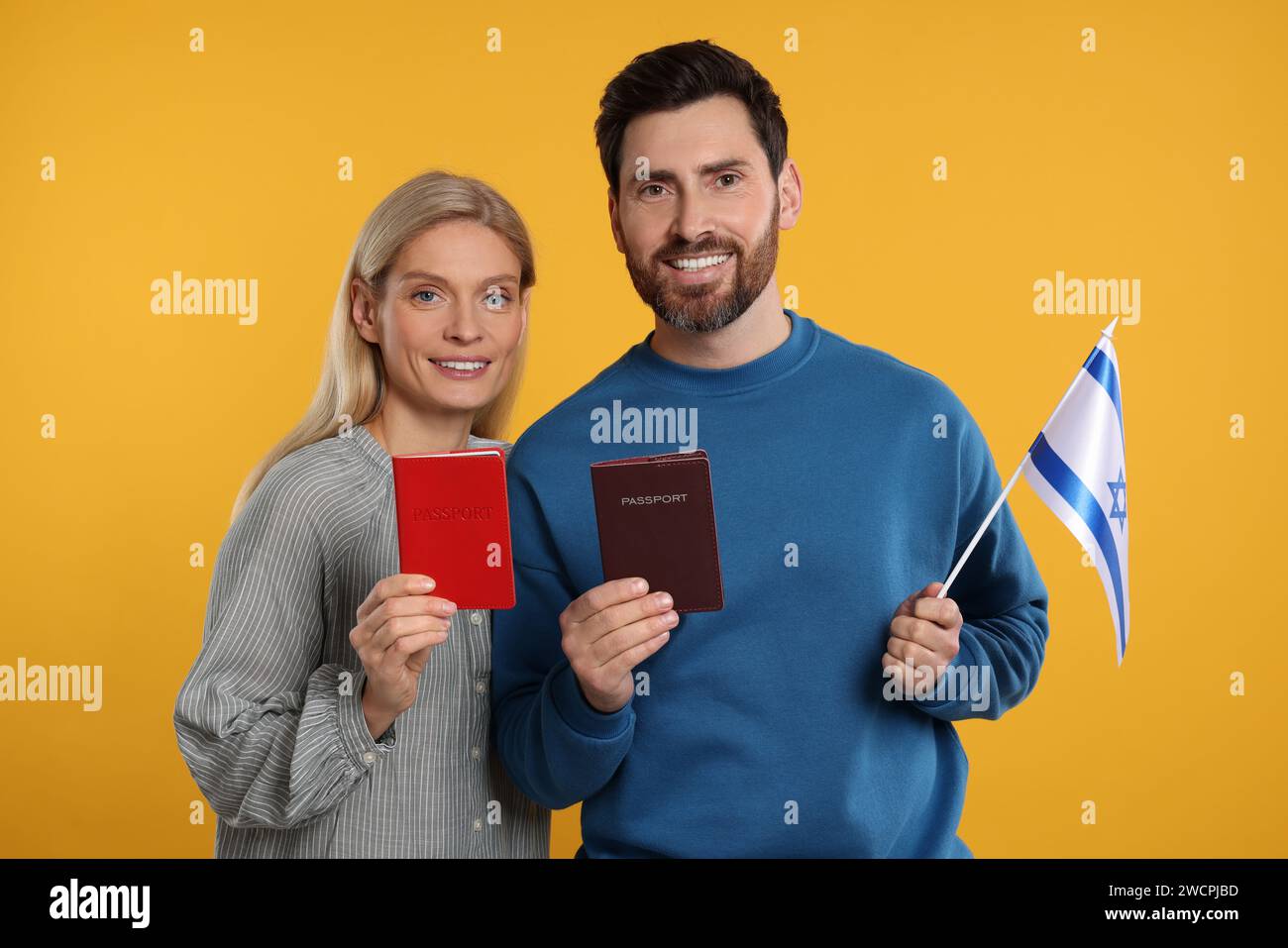 Immigration. Happy couple with passports and flag of Israel on orange ...