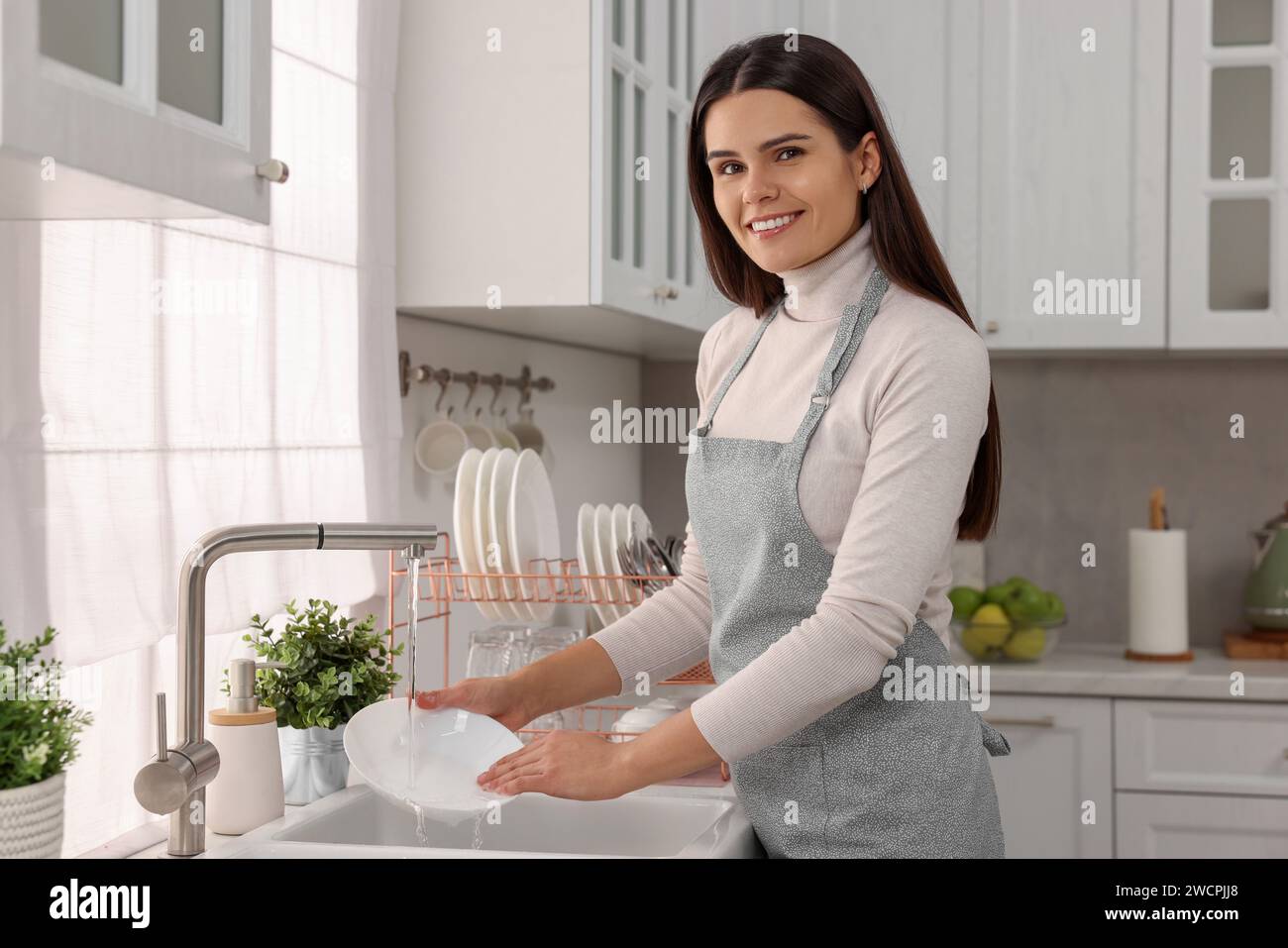 Happy woman washing bowl at sink in kitchen Stock Photo - Alamy