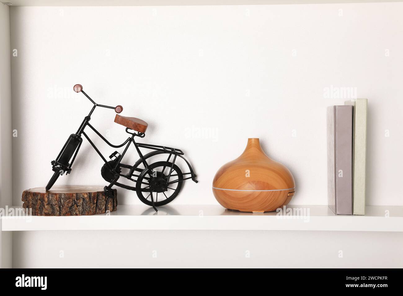 White shelf with books, air humidifier and bicycle figure indoors ...