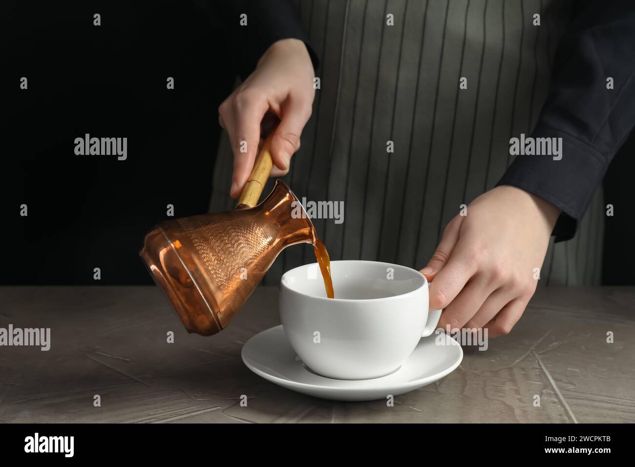 Turkish coffee. Woman pouring brewed beverage from cezve into cup at ...