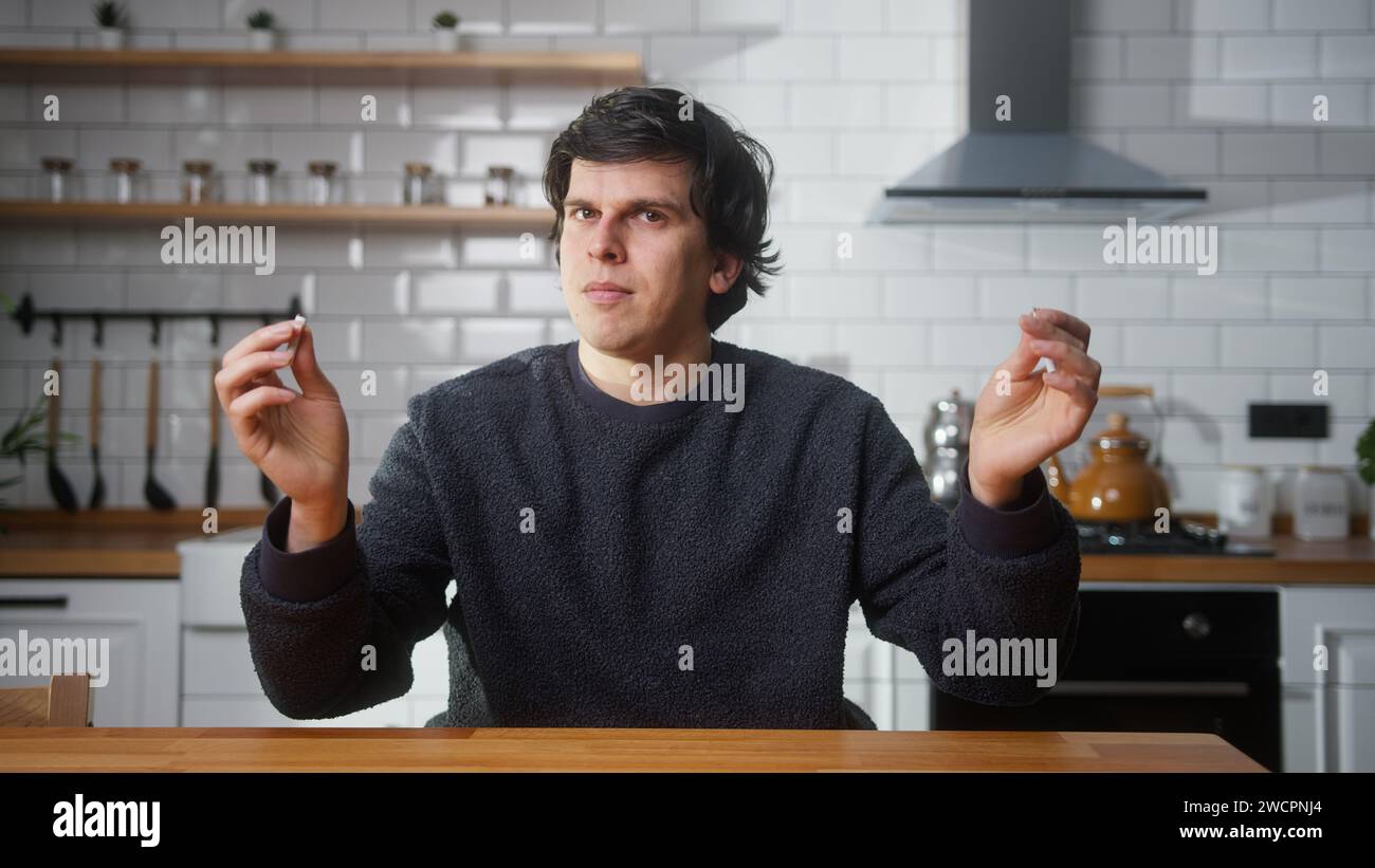 Man broke a cigarette in two while sitting in modern kitchen. Man quit ...