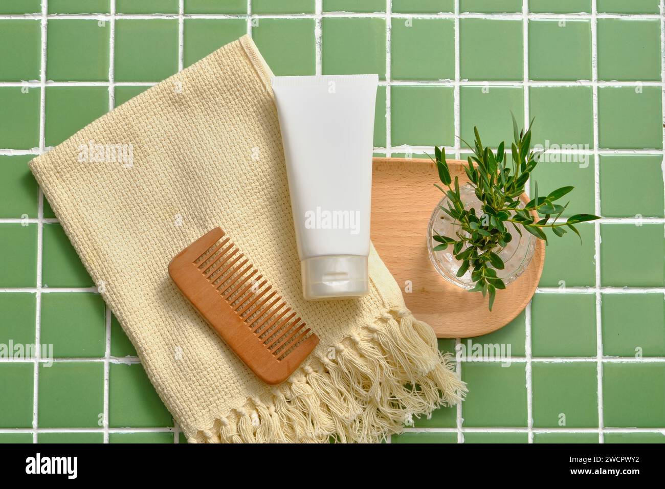 An unlabeled tube in white color, a wooden comb, beige towel and a ...