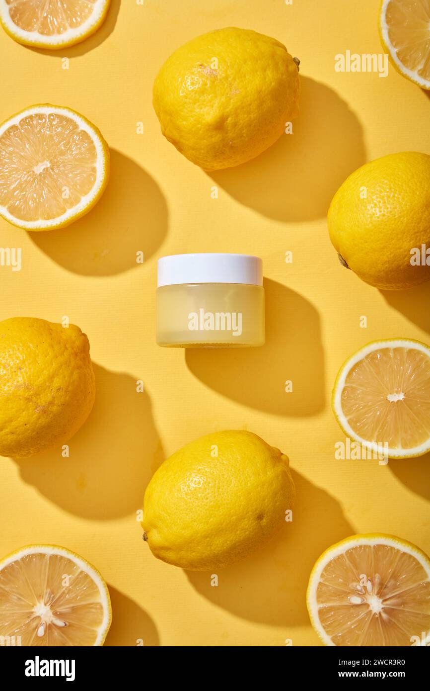 Cosmetic jar with empty label is surrounded by many halves of lemon ...