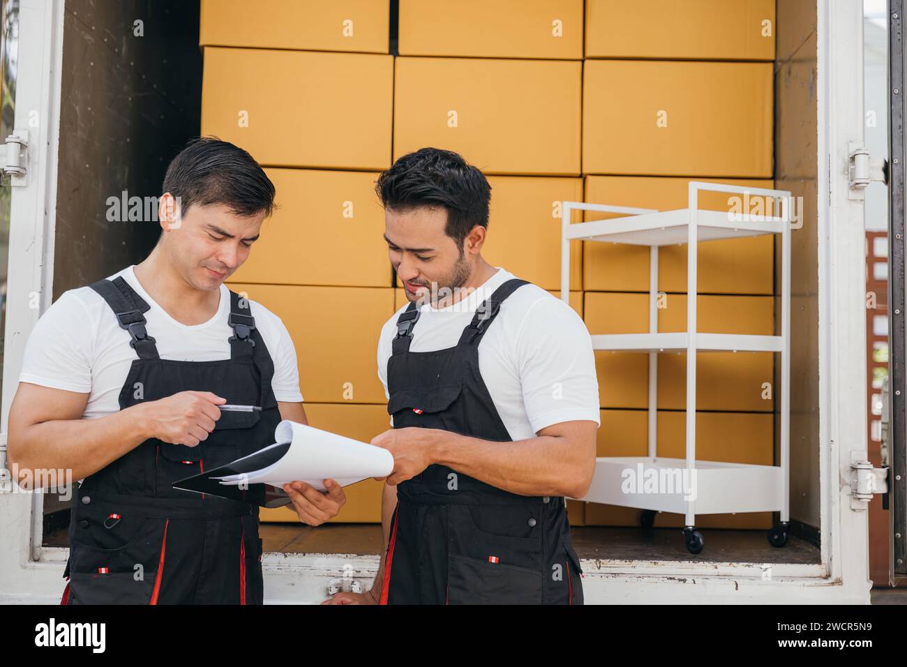 Workers in uniform outdoors unloading boxes and checking list for the ...