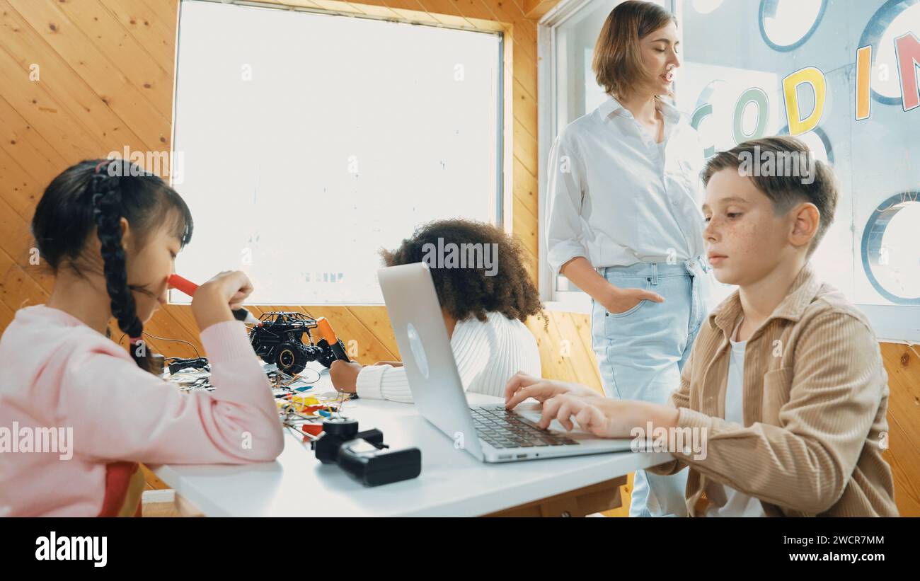 Smart teacher teaching and looking student using laptop at classroom ...