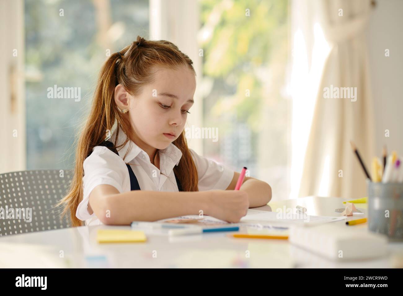 Creative schoolgirl drawing in textbook at school desk Stock Photo - Alamy