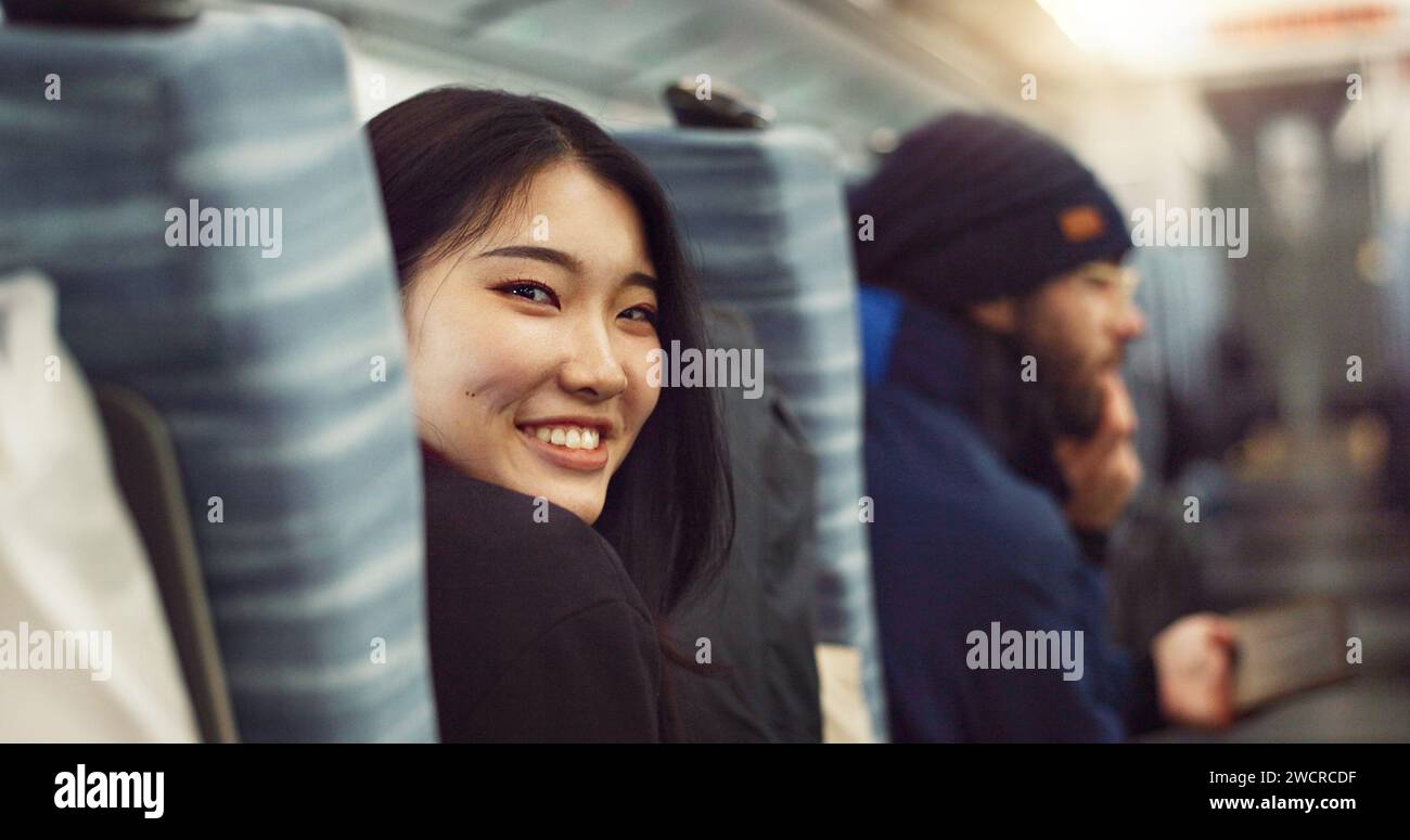 Smile, face and young Asian woman on a train for public transportation ...