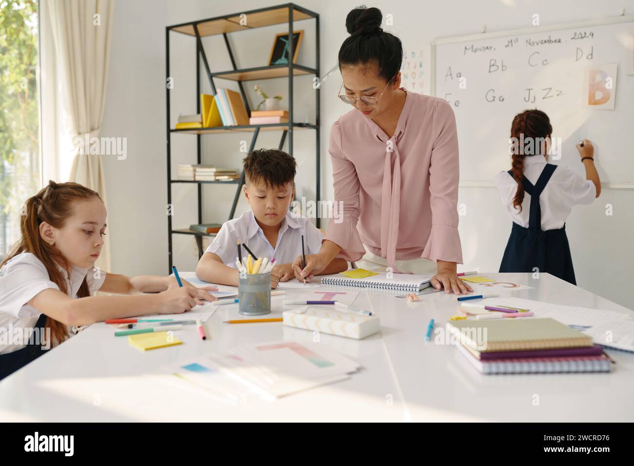 Teacher showing kids how to write letters in class Stock Photo - Alamy