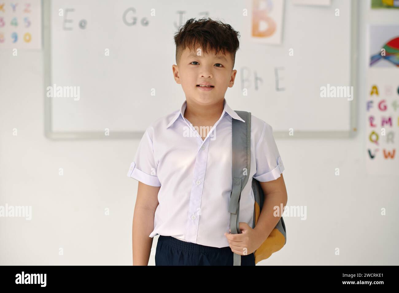 Portrait of smiling schoolkid with backpack standing in class Stock ...