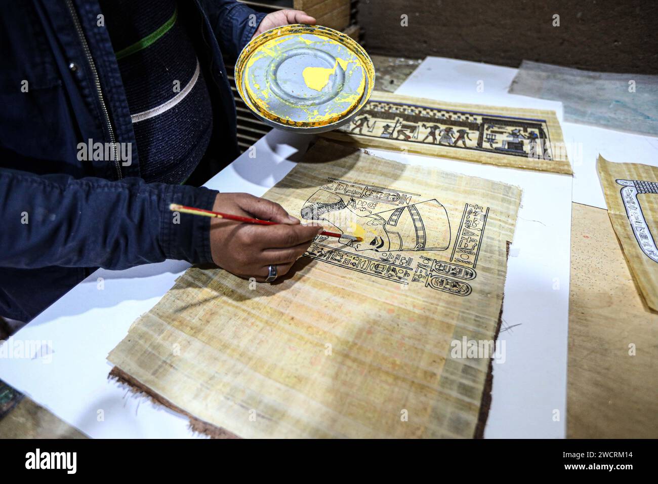 Sharqiya, Egypt. 16th Jan, 2024. An artist colors a papyrus paper ...