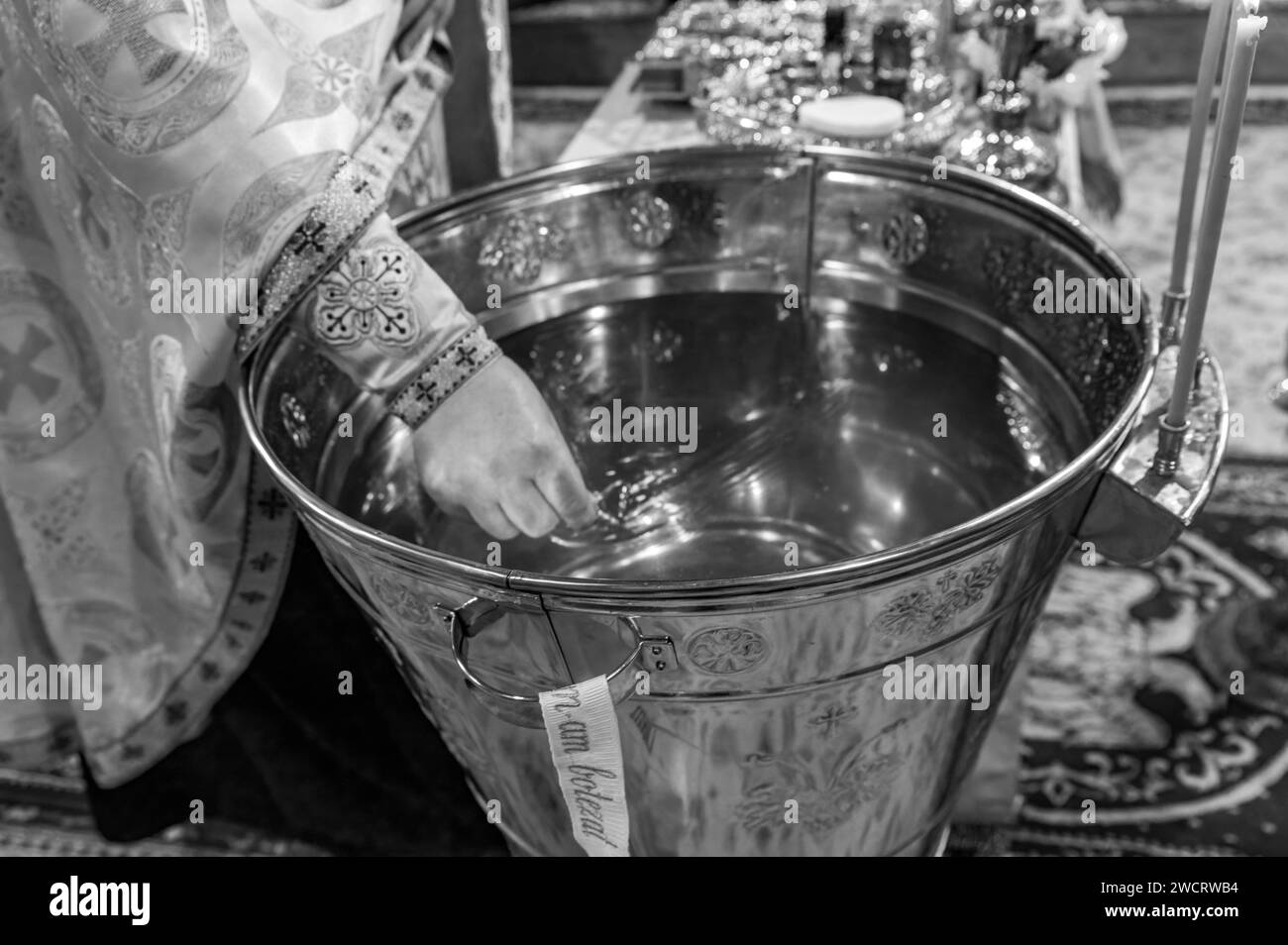 baptismal font with water for the Orthodox baptism in the church, with the priest nearby ...
