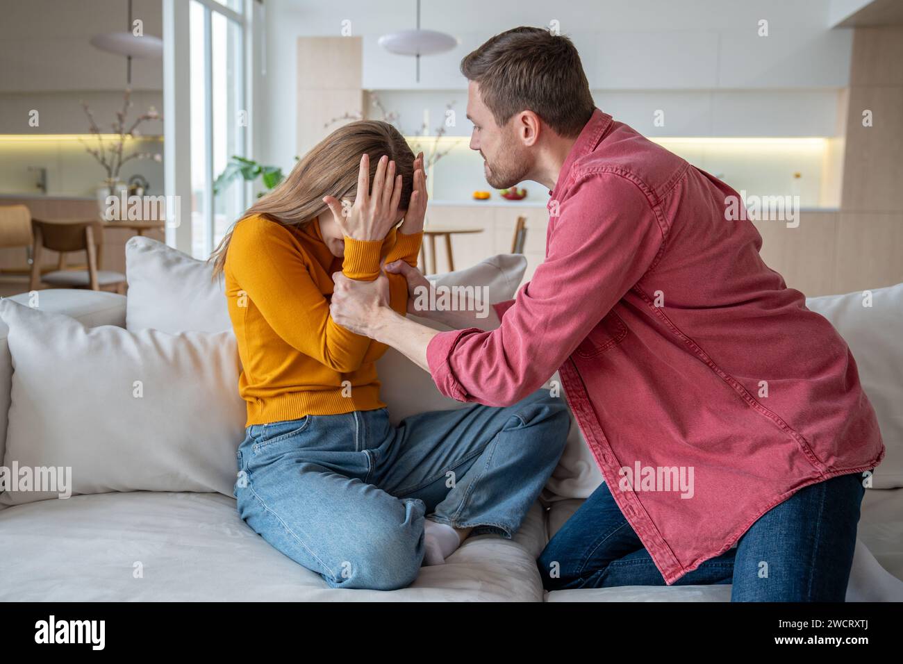 Furious husband quarreling, shouting at wife. Scared woman hiding face ...
