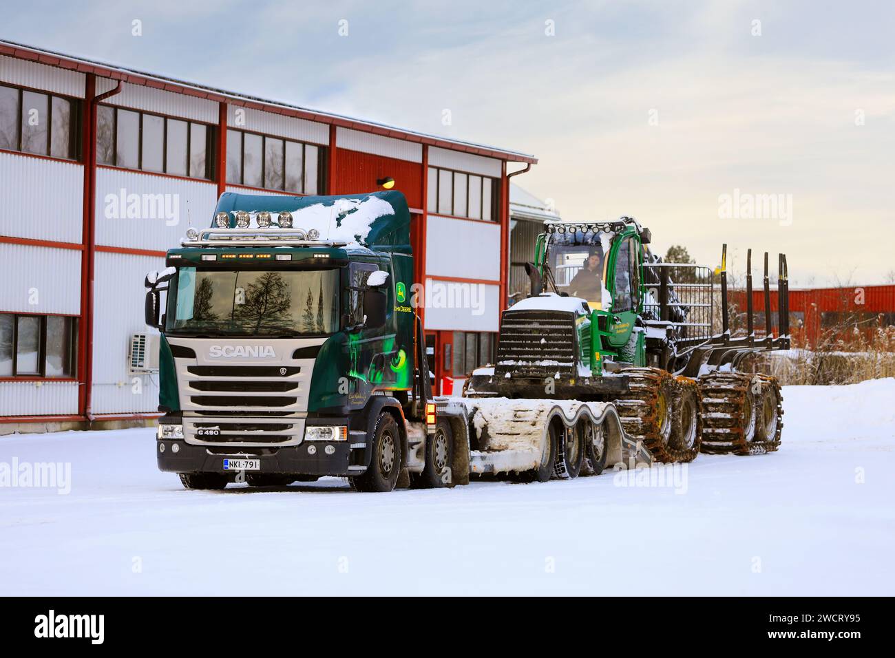 Loading John Deere 1210E forestry forwarder onto Scania G490 truck ...