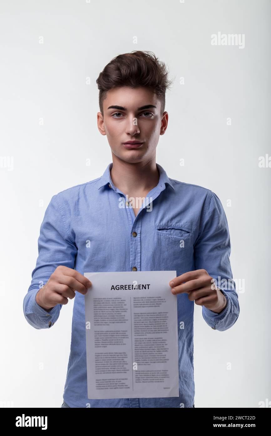 With a serious expression, the man holds an 'Agreement' document ...