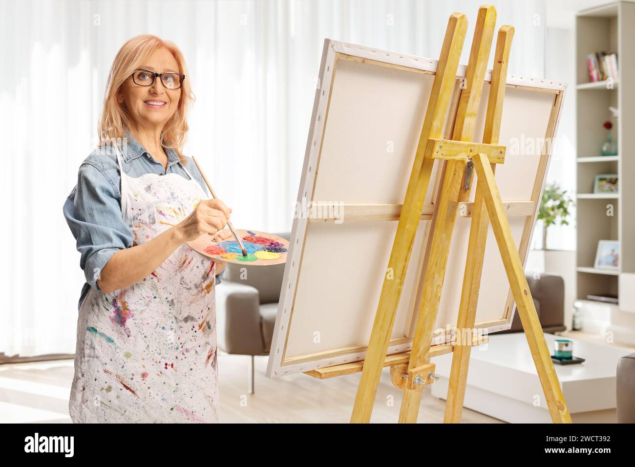 Woman with an apron painting on a canvas at home Stock Photo - Alamy