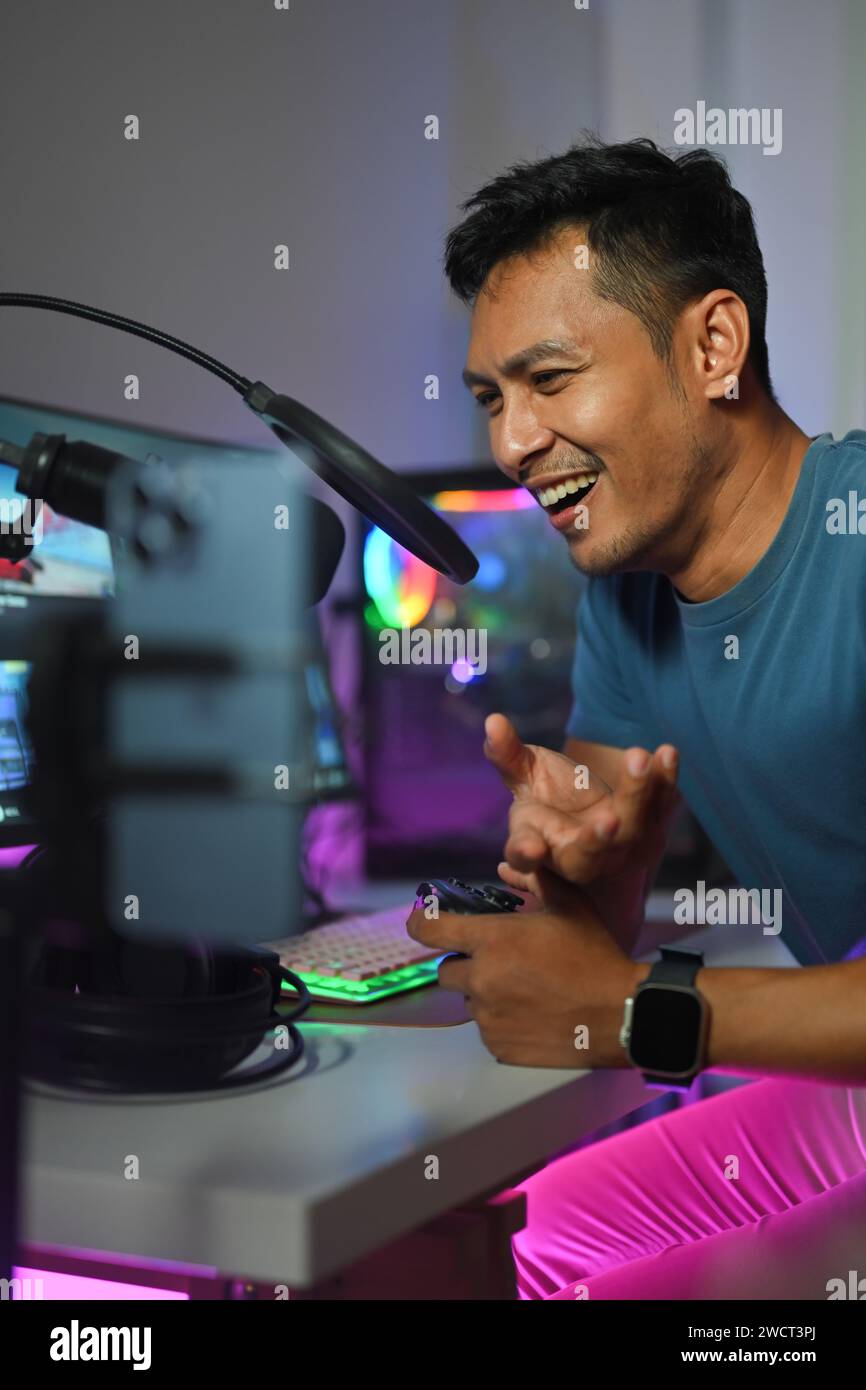 Smiling young adult gamer talking to audience through microphone during ...