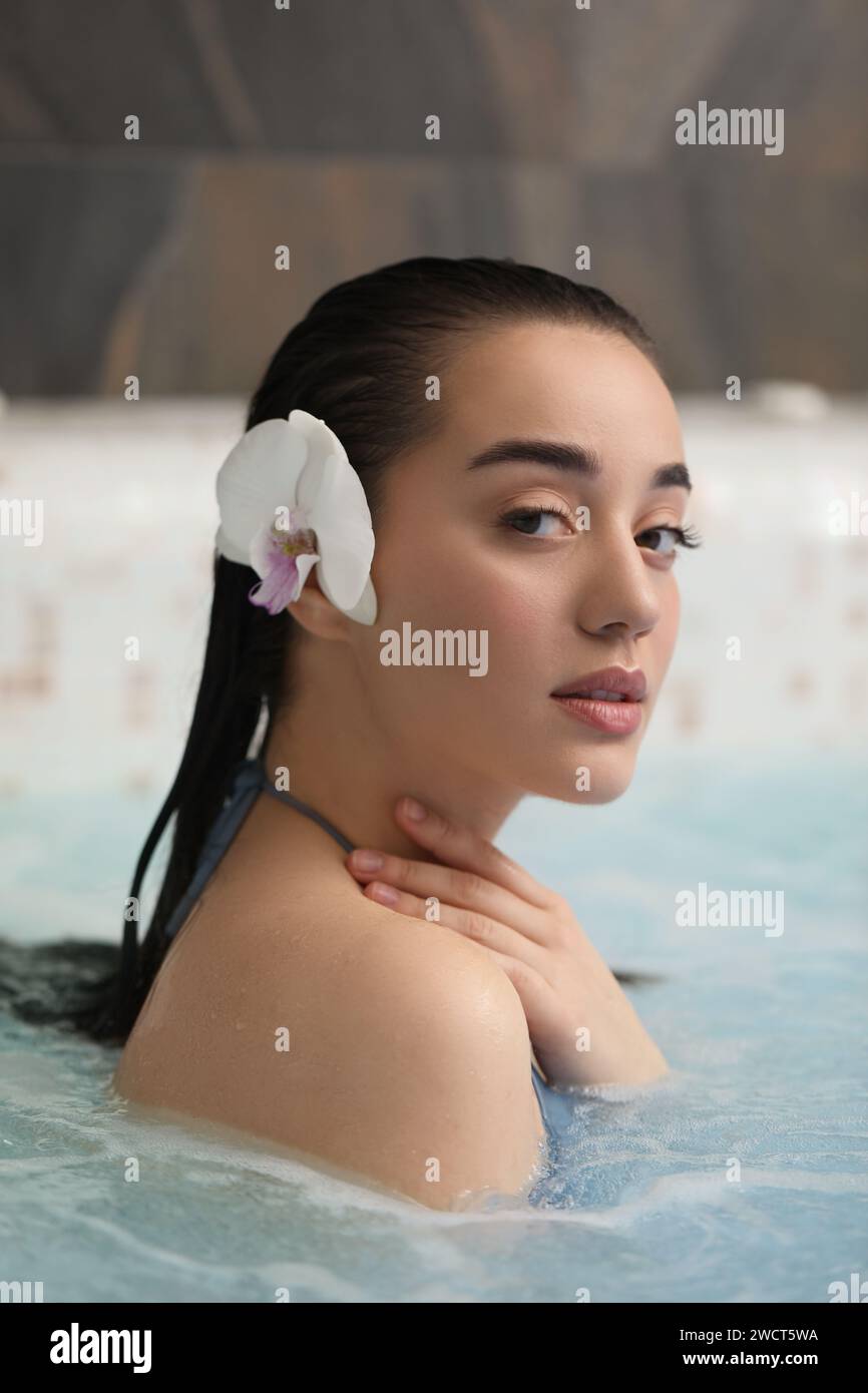 Beautiful woman with orchid flower in spa swimming pool Stock Photo - Alamy
