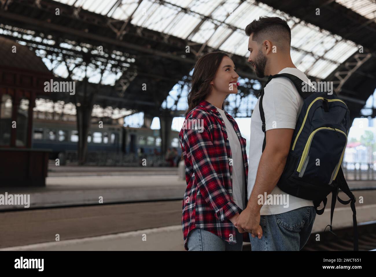 Long-distance relationship. Beautiful couple on platform of railway station, space for text ...