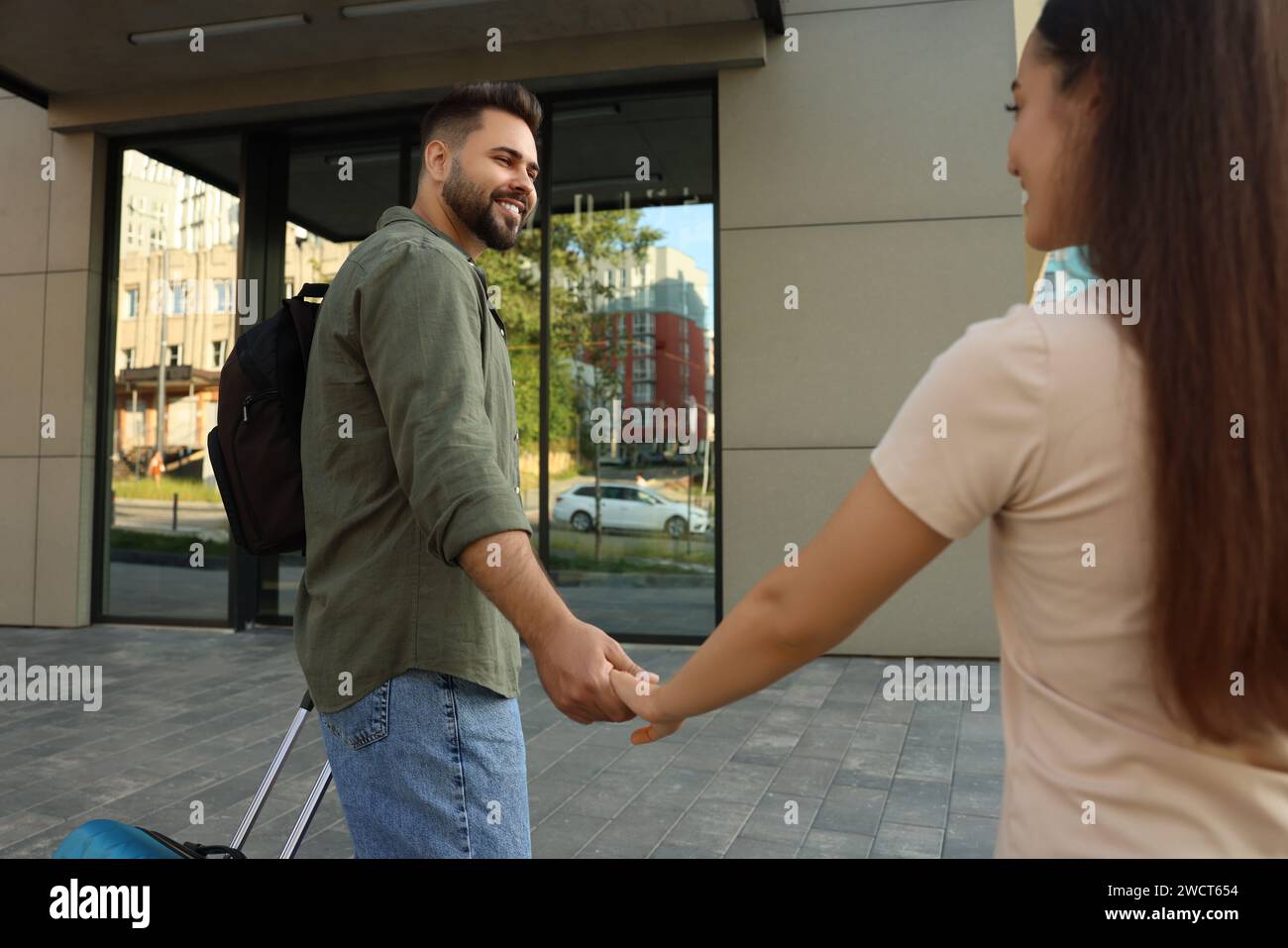 Long-distance relationship. Man with luggage holding hands with his ...