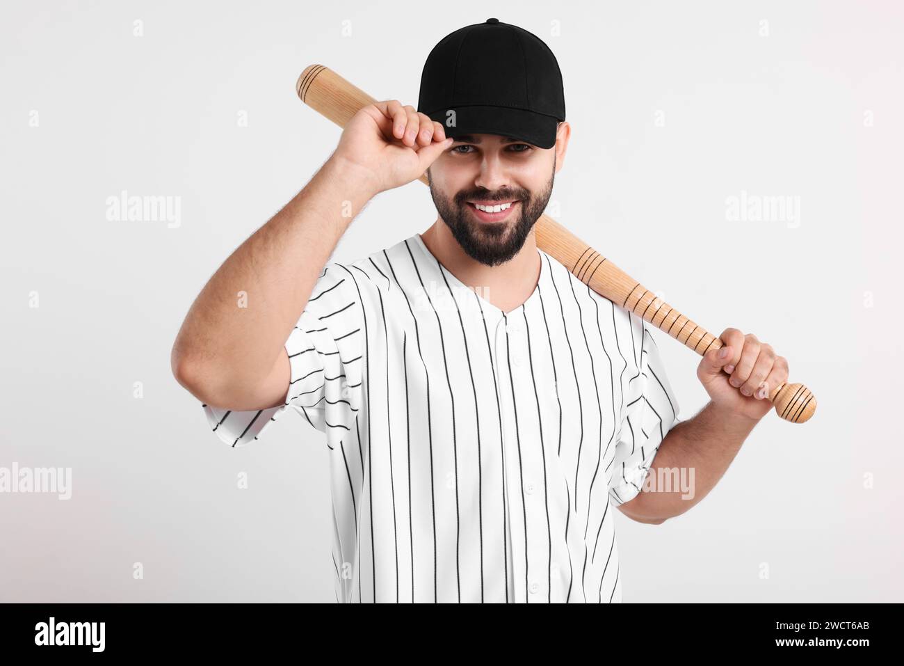 Man in stylish black baseball cap holding bat on white background Stock ...