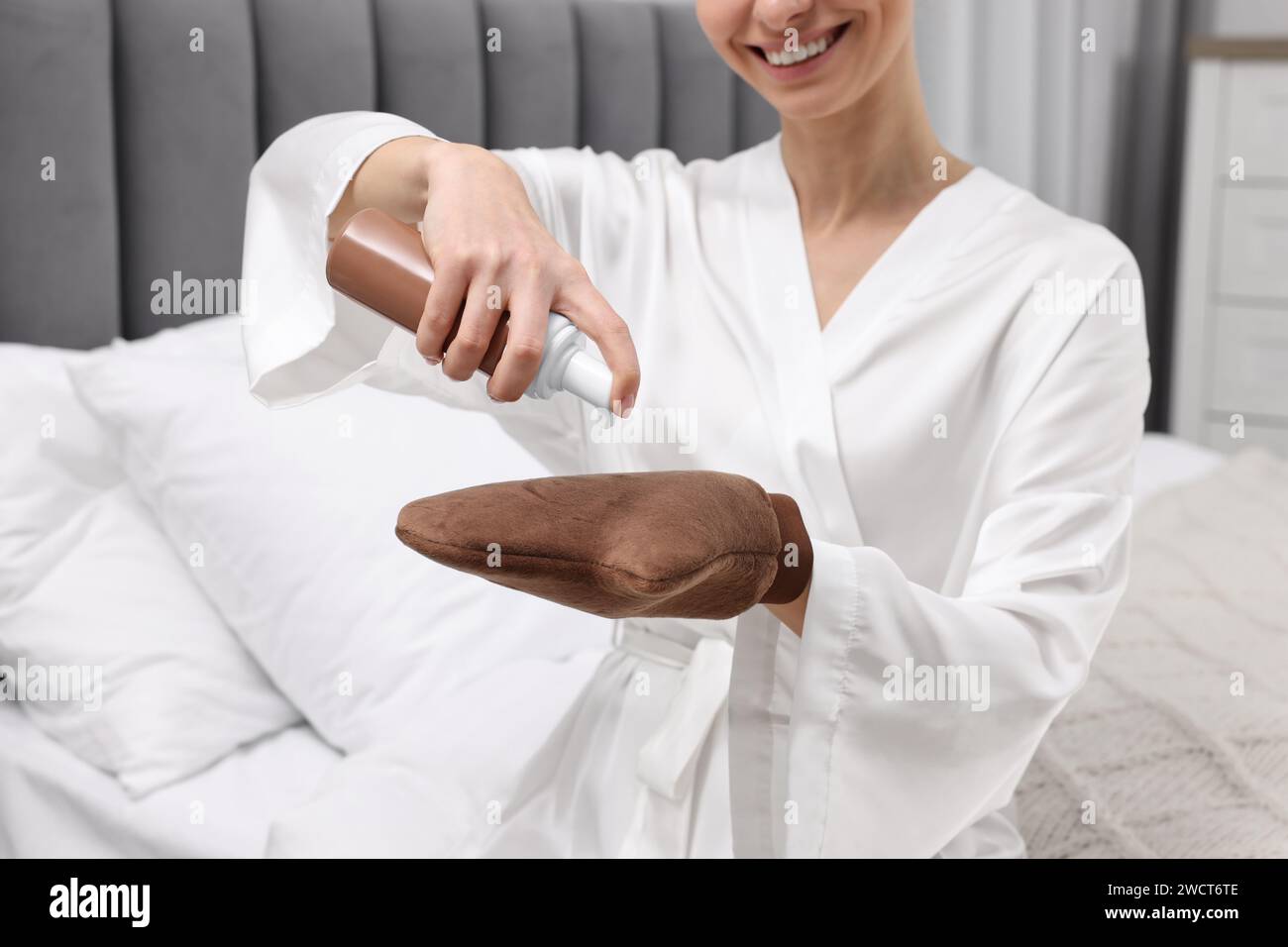 Self-tanning. Woman applying cosmetic product onto tanning mitt in ...