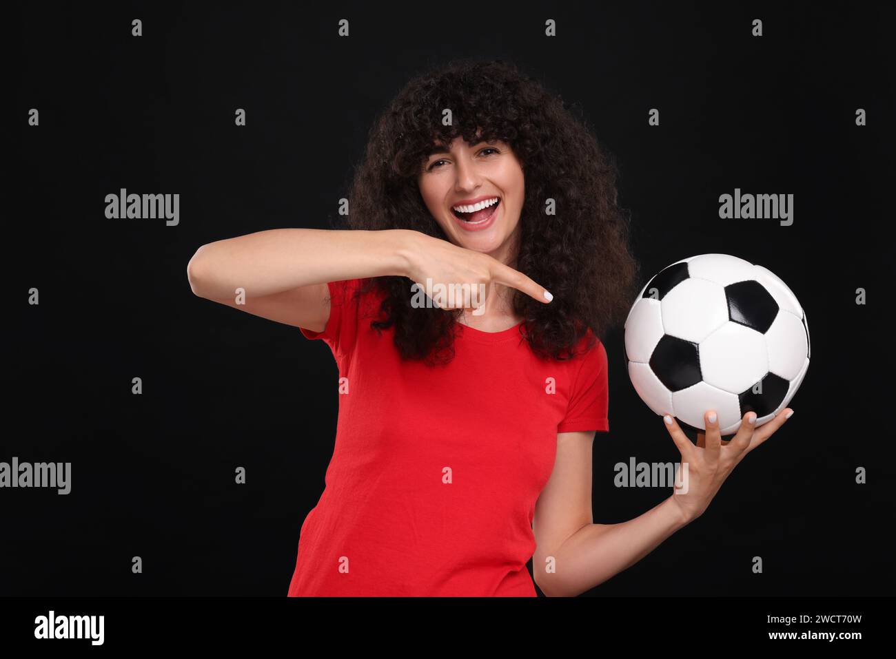 Happy fan showing soccer ball on black background Stock Photo - Alamy