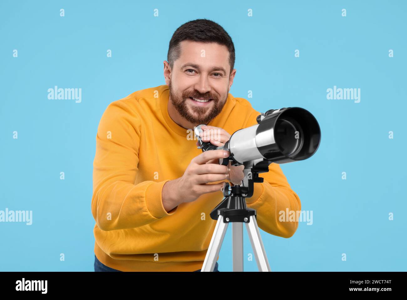 Happy astronomer with telescope on light blue background Stock Photo ...