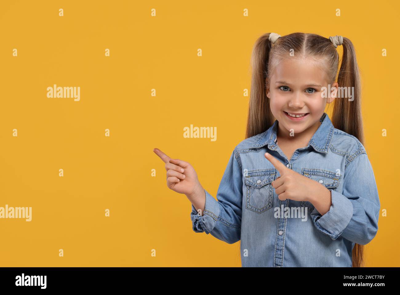 Special promotion. Little girl pointing at something on orange ...