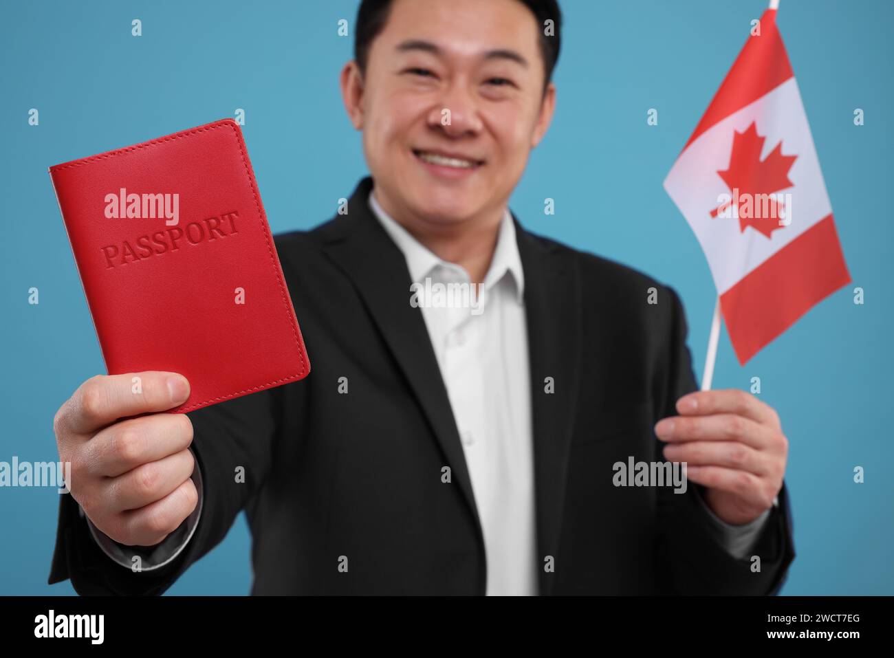 Immigration. Happy man with passport and flag of Canada on light blue ...