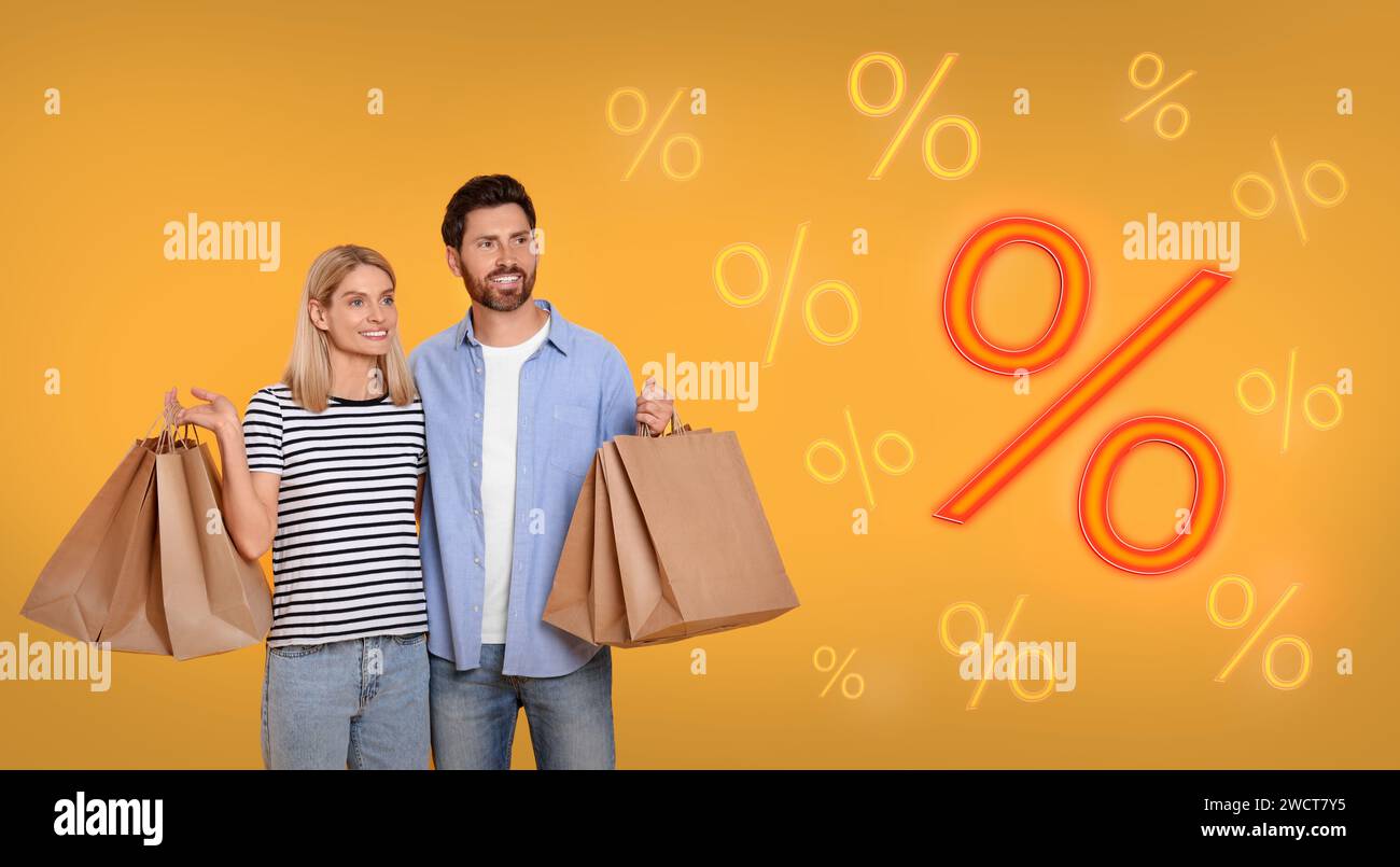 Discount offer. Couple with shopping bags looking at percent signs on ...