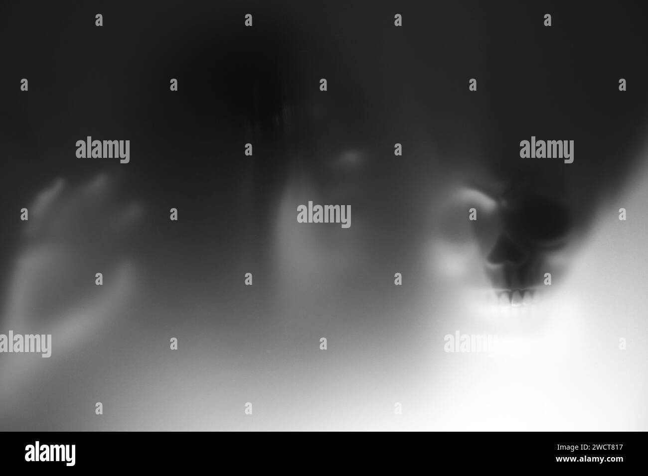 Silhouette of creepy ghost with skull behind glass against grey ...