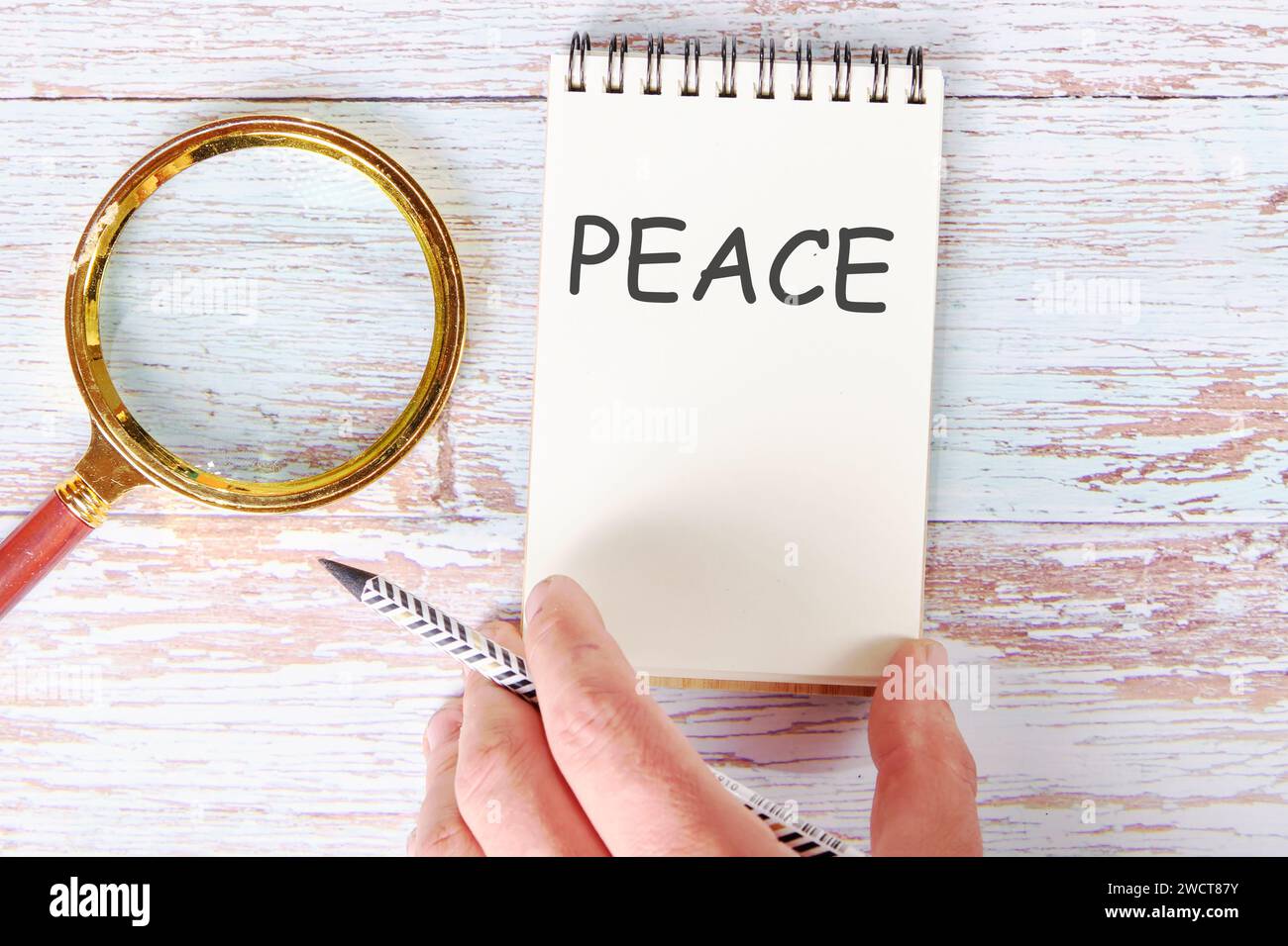 PEACE written on a blank sheet of a notebook which is touched by a man ...