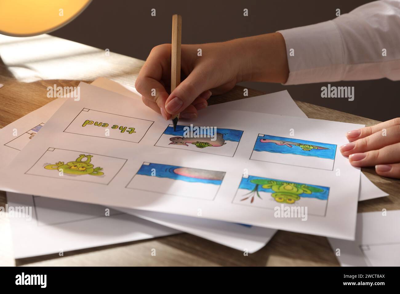 Woman drawing cartoon sketch in storyboard at workplace, closeup. Pre ...